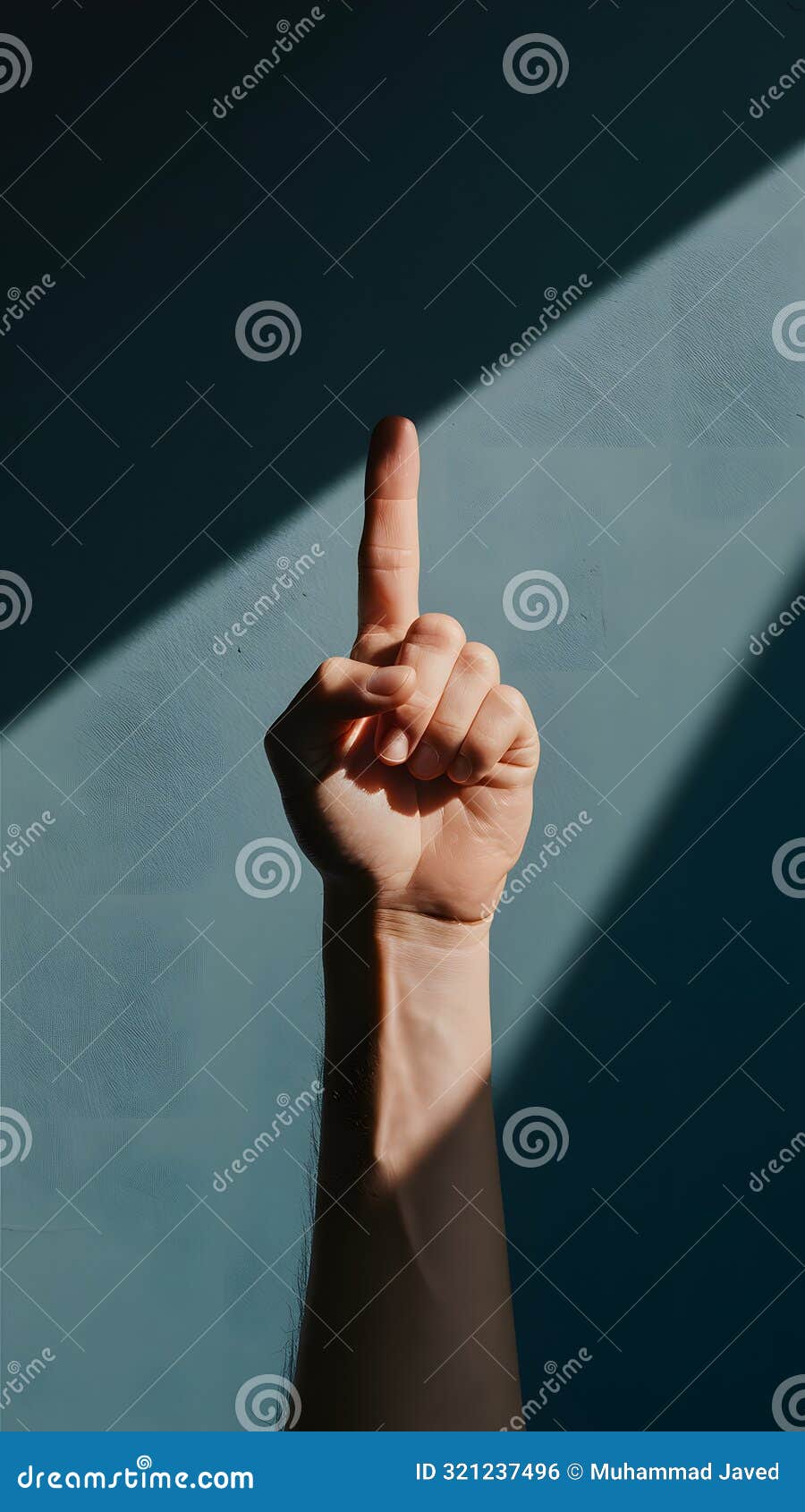 Hand Pointing Upwards in Shadow, Illuminated Against Soft Blue ...