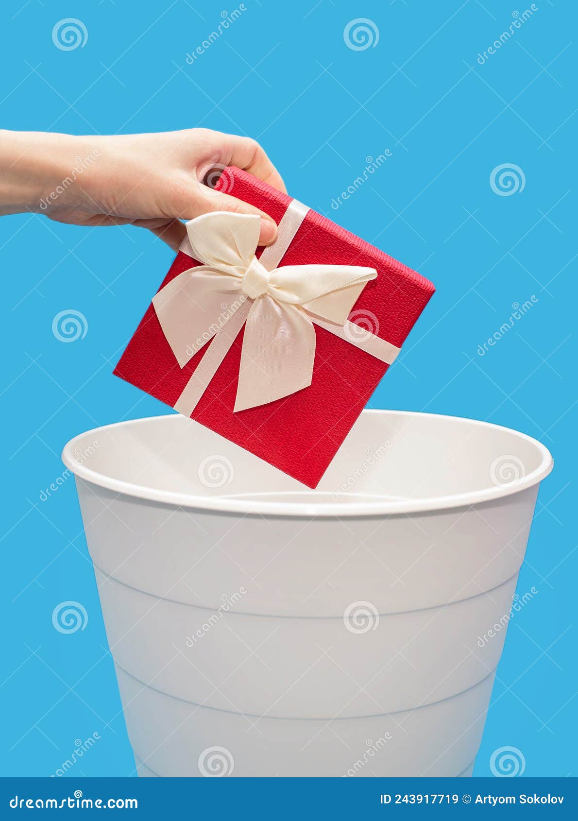Human Throws a Gift Box into a Trash Can on a Blue Background Stock ...