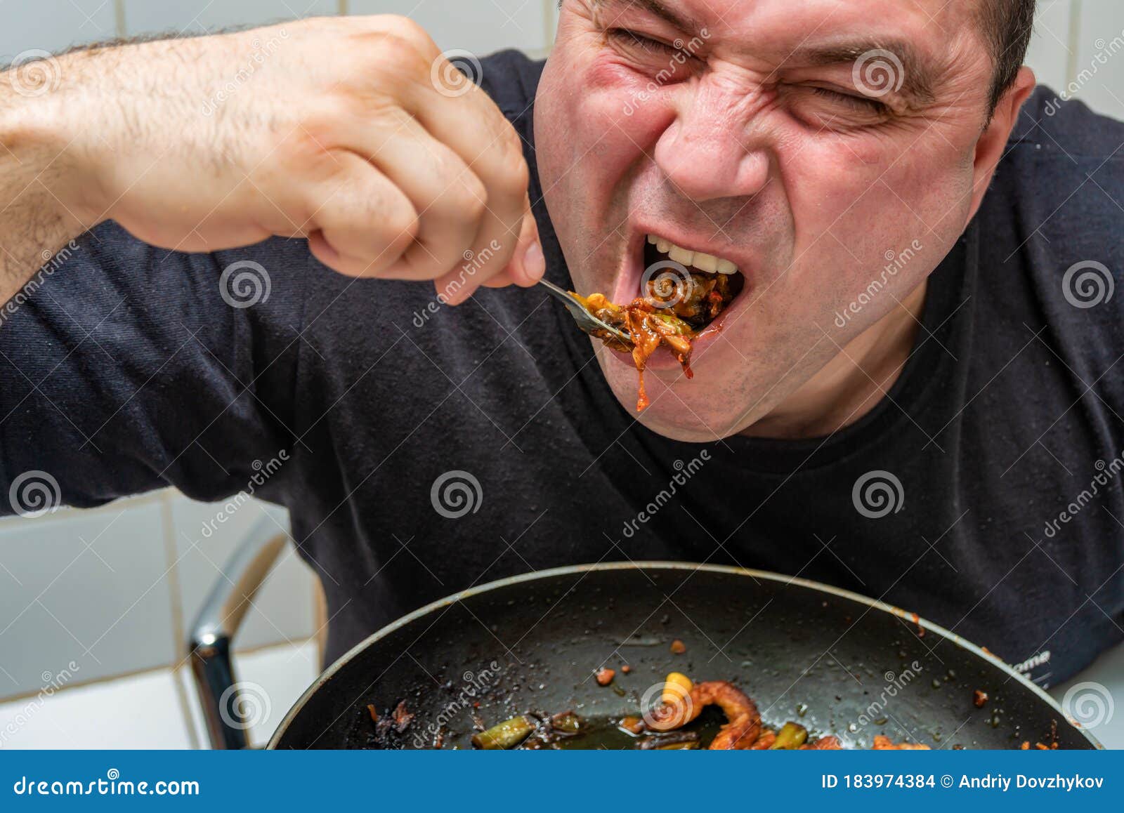 A Hungry Man Eagerly Eats Fried Meat with Sauce from a Fork Stock Photo ...