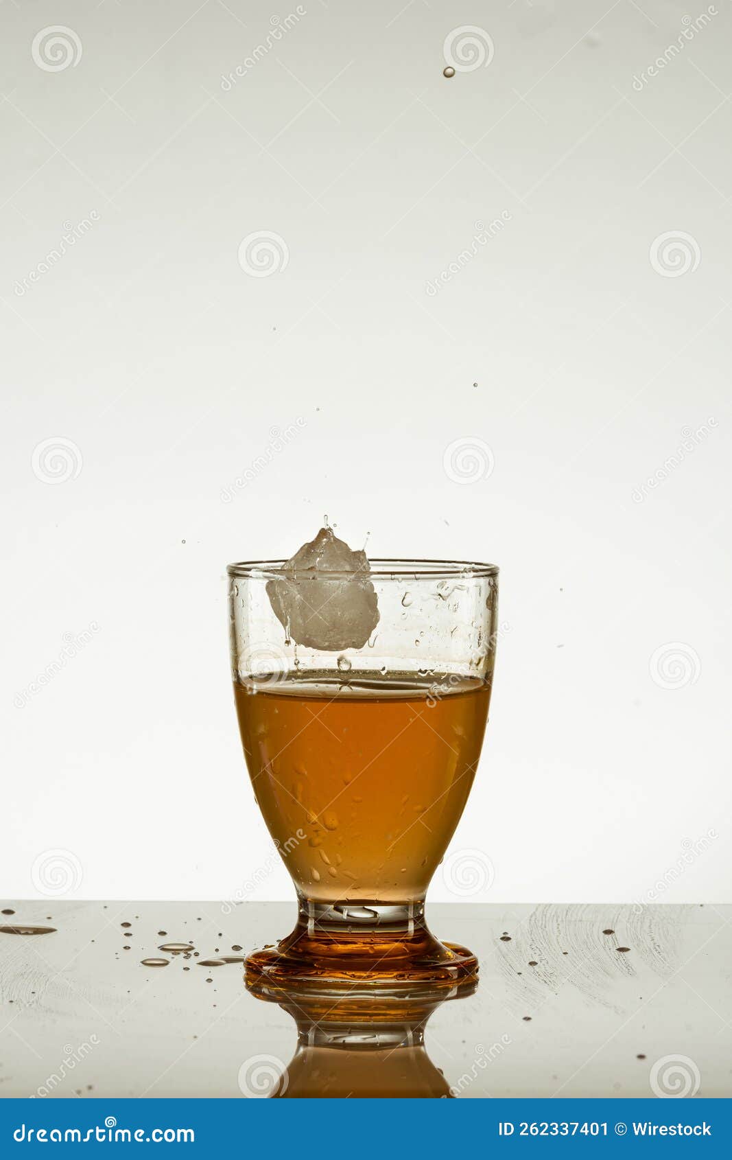 Ice Cube Falling into a Glass of Yellow Drink Isolated on the ...