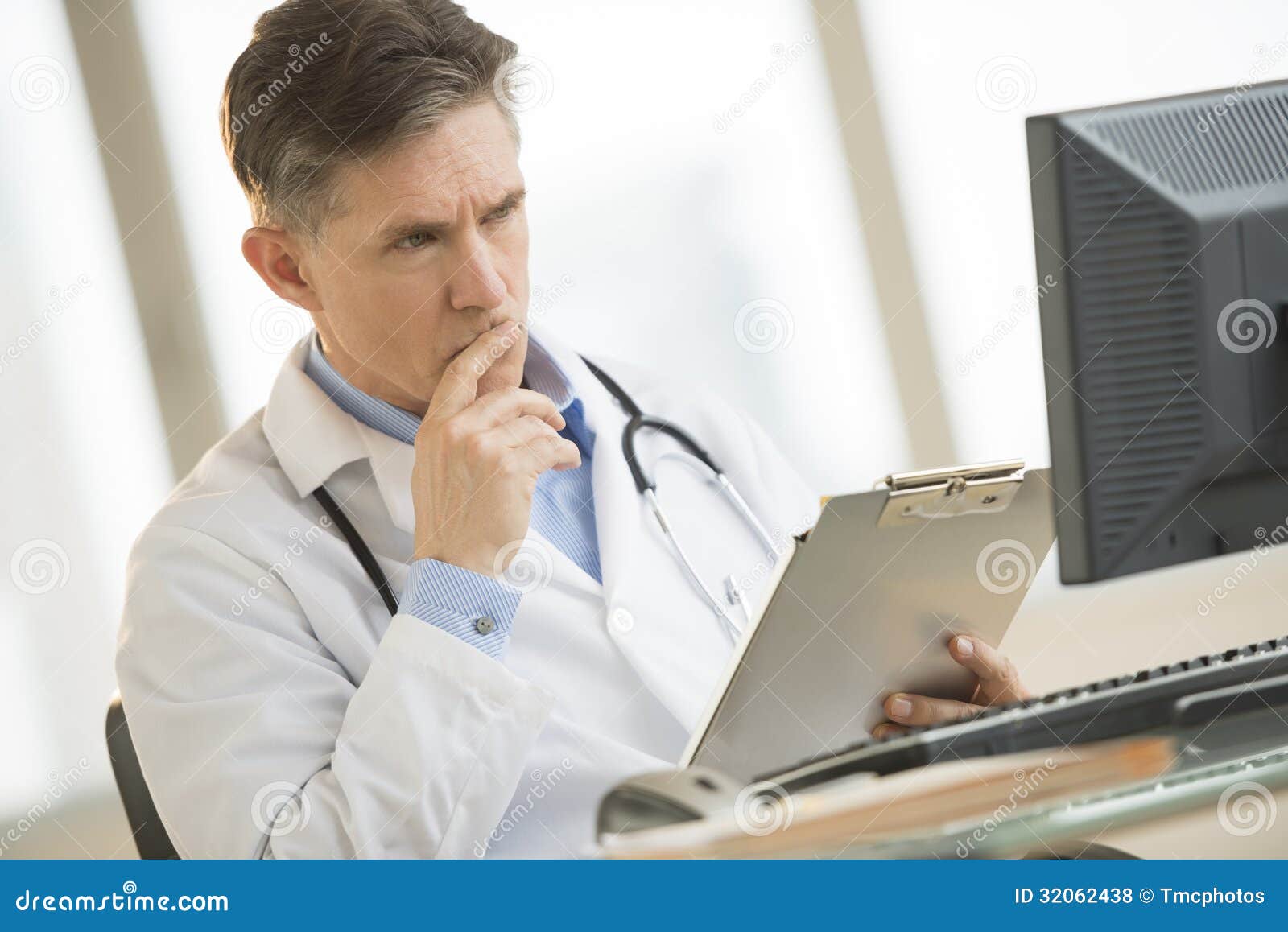 Il Dottore Serio Looking at Computer Mentre Tenendo Lavagna Per Appunti ...