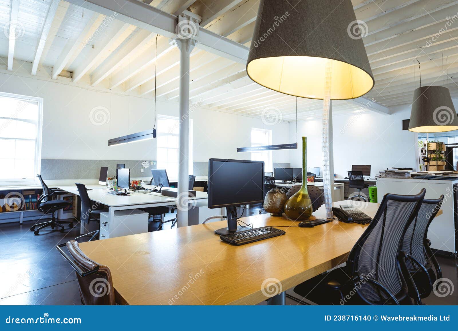 Illuminated Pendant Light Over Desk with Computers in Modern Office ...