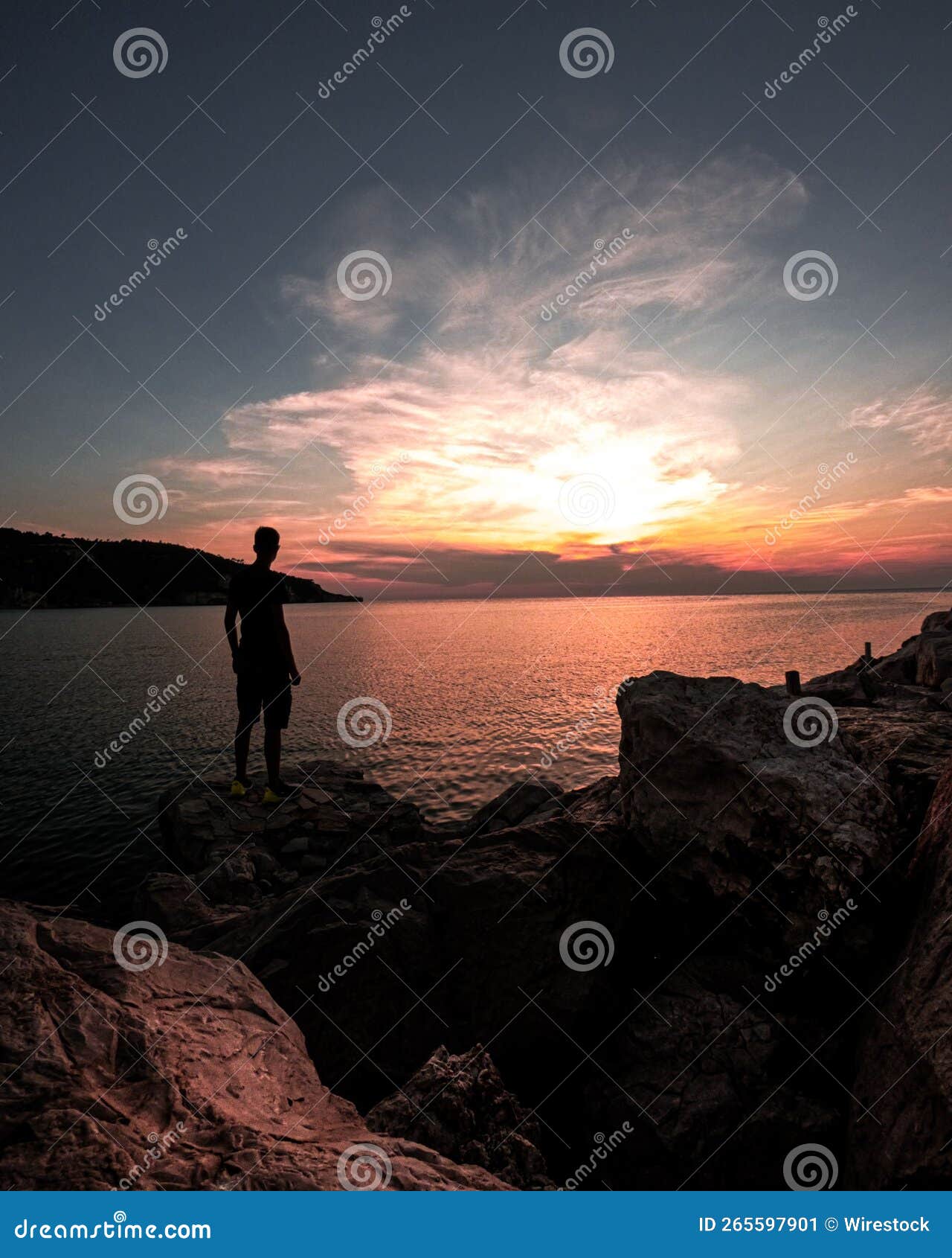 Image of a Boy Standing on the Rocks Looking at the Sea and Dark Red ...