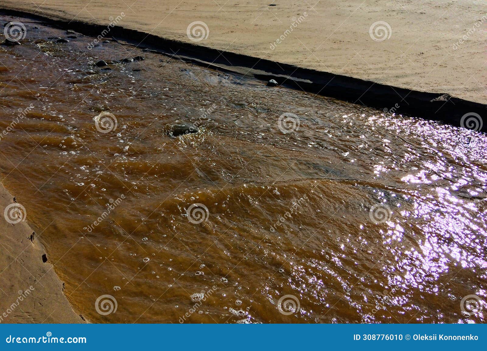 The Image Captures a Muddy Stream Flowing Across a Sandy Surface, with ...
