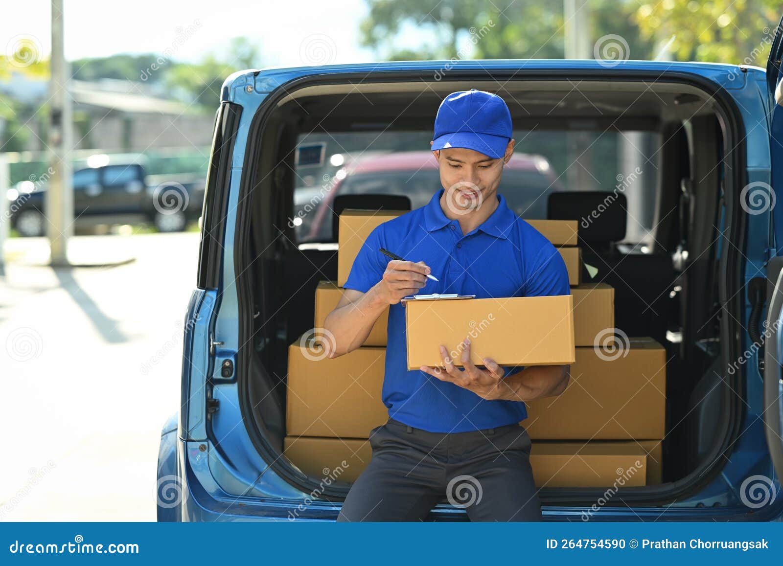 Image of Delivery Man Sitting in Open Delivery Van and Checking ...
