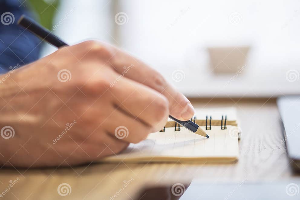Man S Hand Scribbling in a Notepad, Set Against a Blurry Scene Stock ...