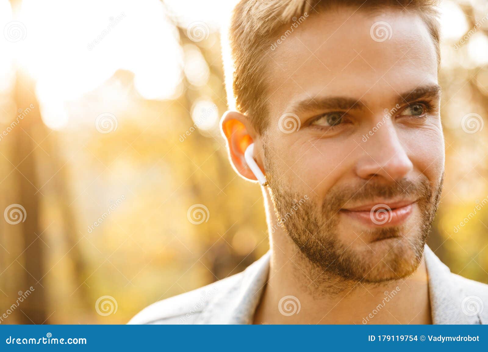 Image of Handsome Young Caucasian Man Using Earbuds while Walking in ...