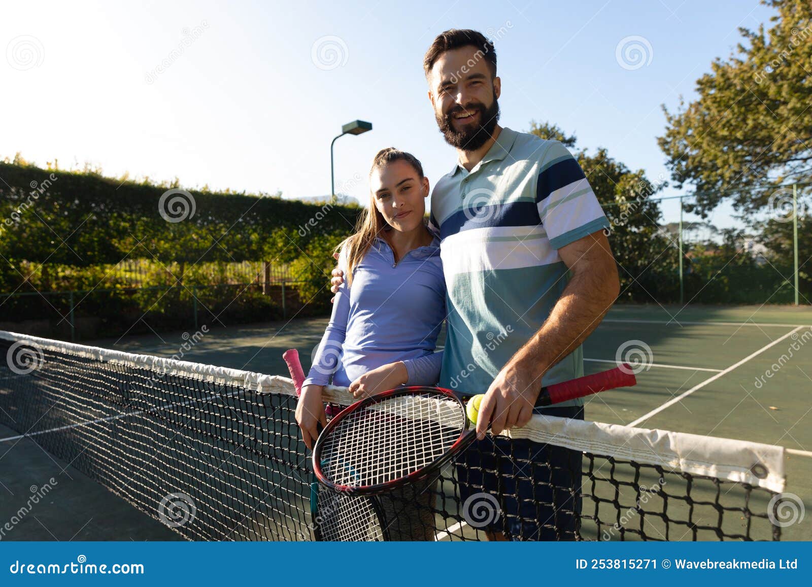 Image Of Happy Caucasian Couple Posing With Rackets On Tennis Court