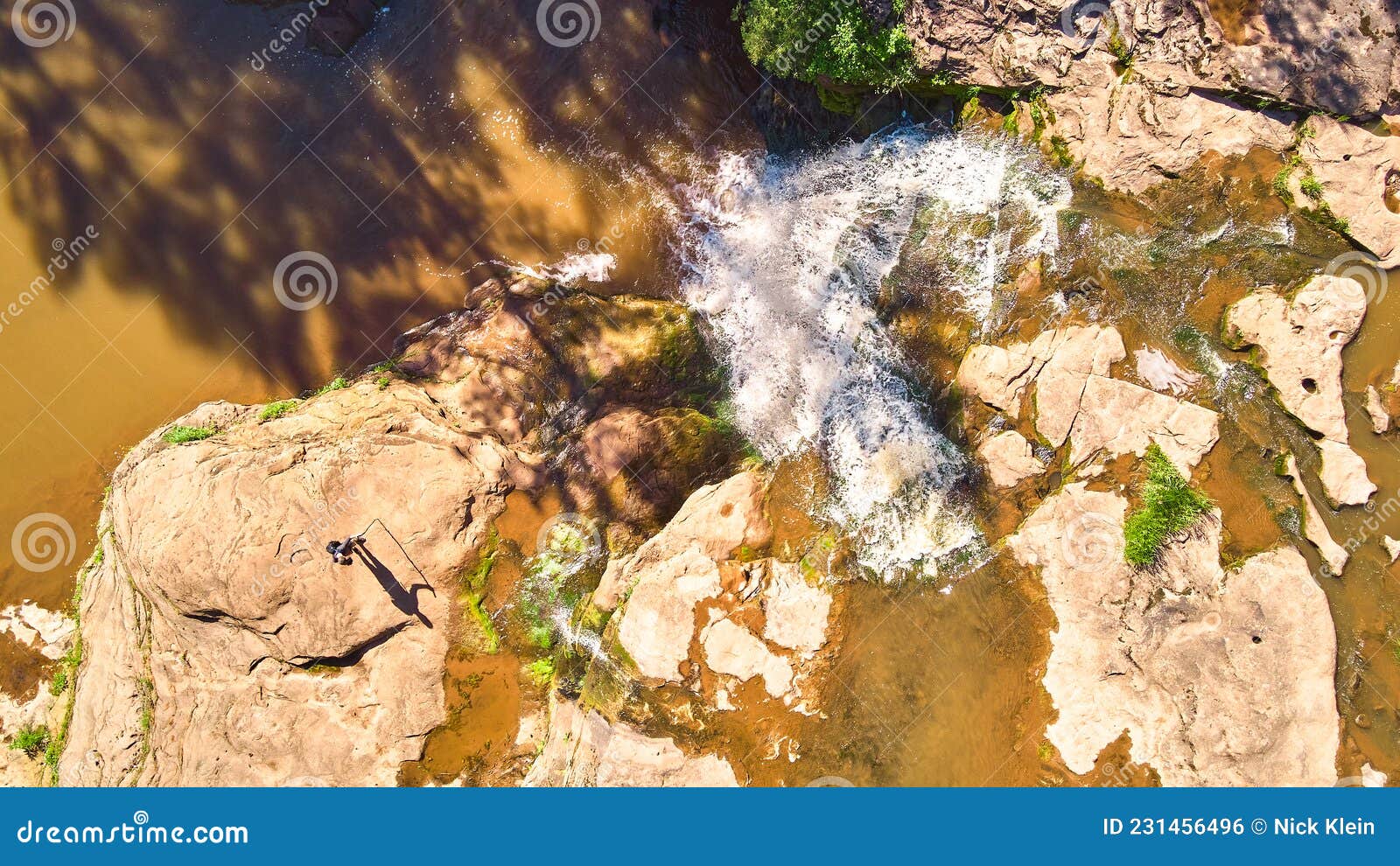 Looking Straight Down at Brown River with Large Waterfall and Hiker ...