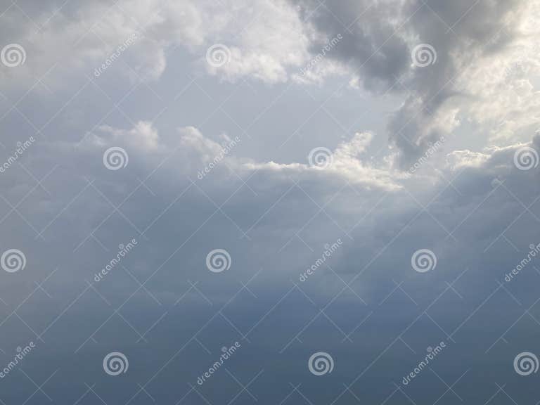 Image Shows a Cloudy Sky with Light Breaking through, Creating a Bright Patch Contrasting Dark ...