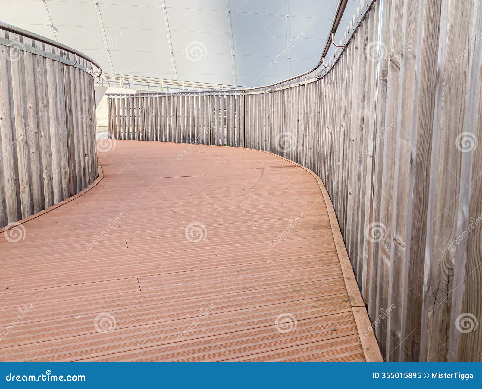 The Image Shows a Curved, Elevated Wooden Walkway with Metal Railing ...