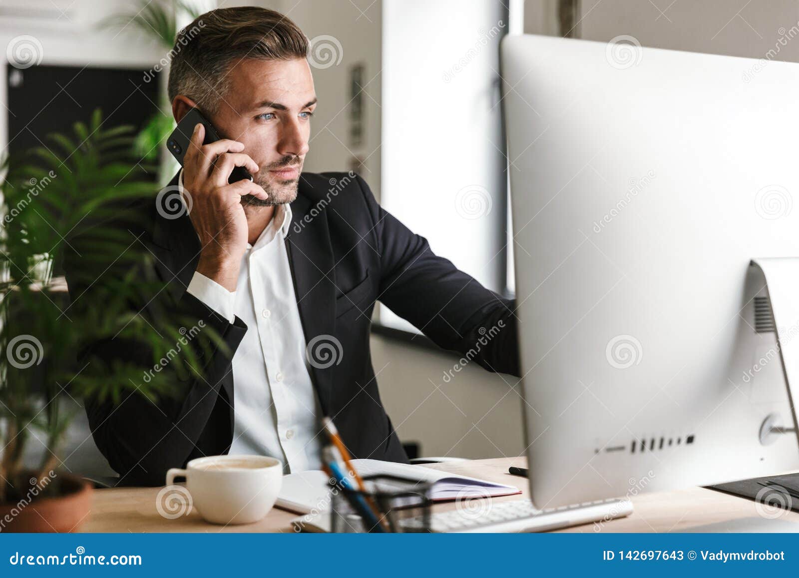 Image of Smart Businessman Talking on Cell Phone while Working on ...