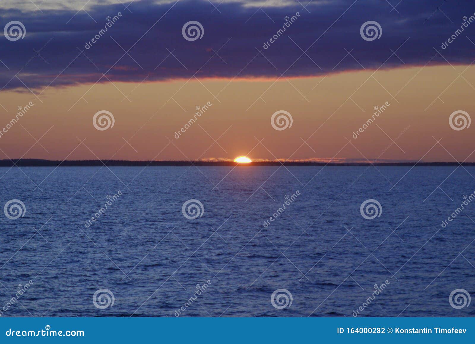Image of the Sun Setting in the Sea Behind the Island Stock Photo ...