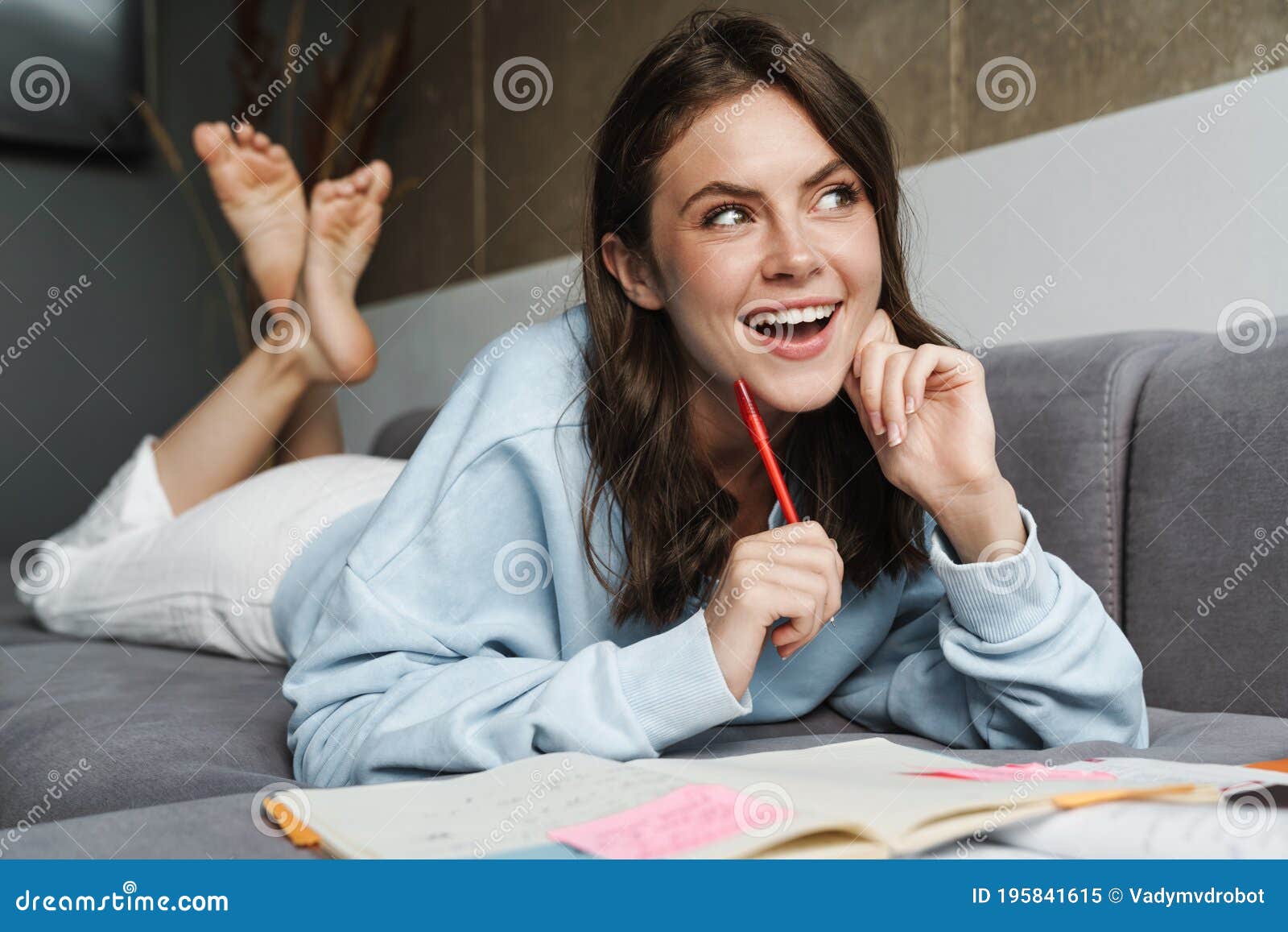 Image of Woman Doing Homework with Exercise Books while Lying on Sofa ...