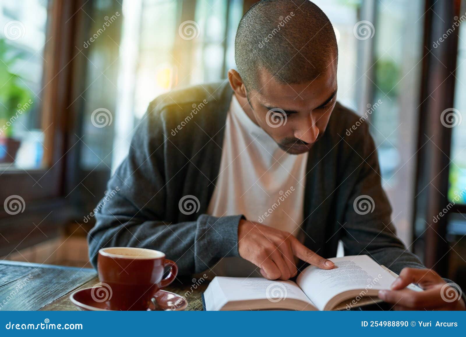 Immersed in a Good Read. a Young Man Reading a Book in a Cafe. Stock ...