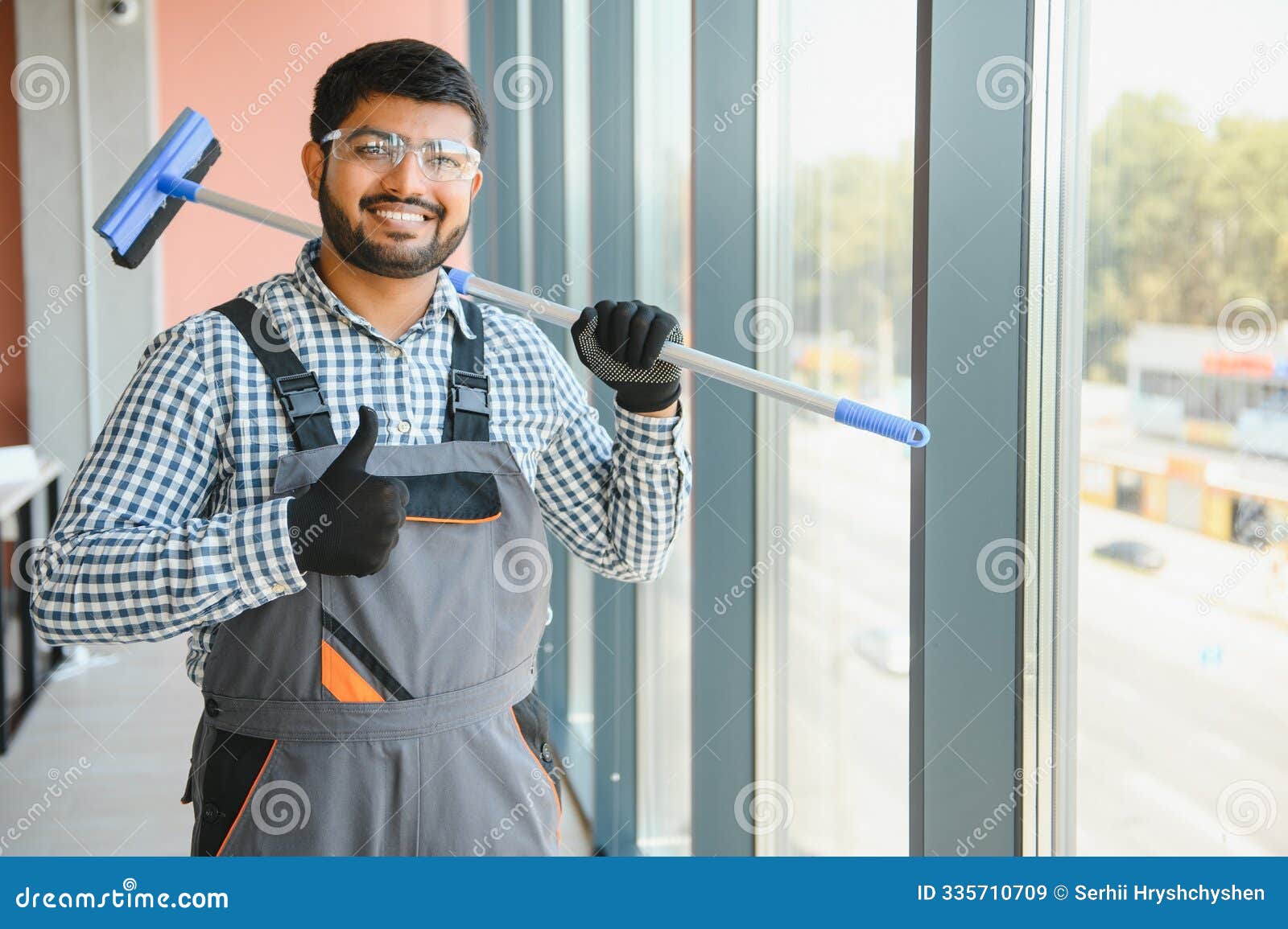 An Indian Cleaning Service Worker Washes Windows in an Office Building ...