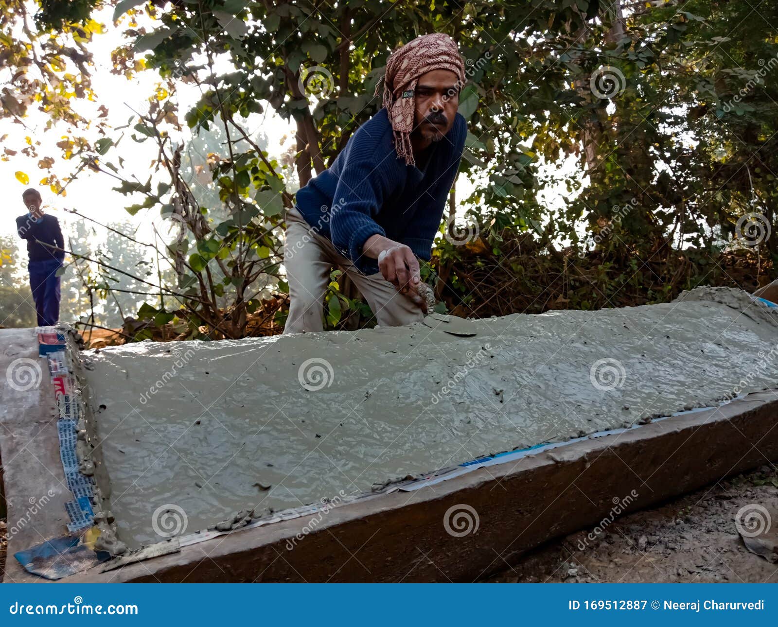 Indian Construction Site With Man Laborer In Hoodie And Helmet Carrying ...