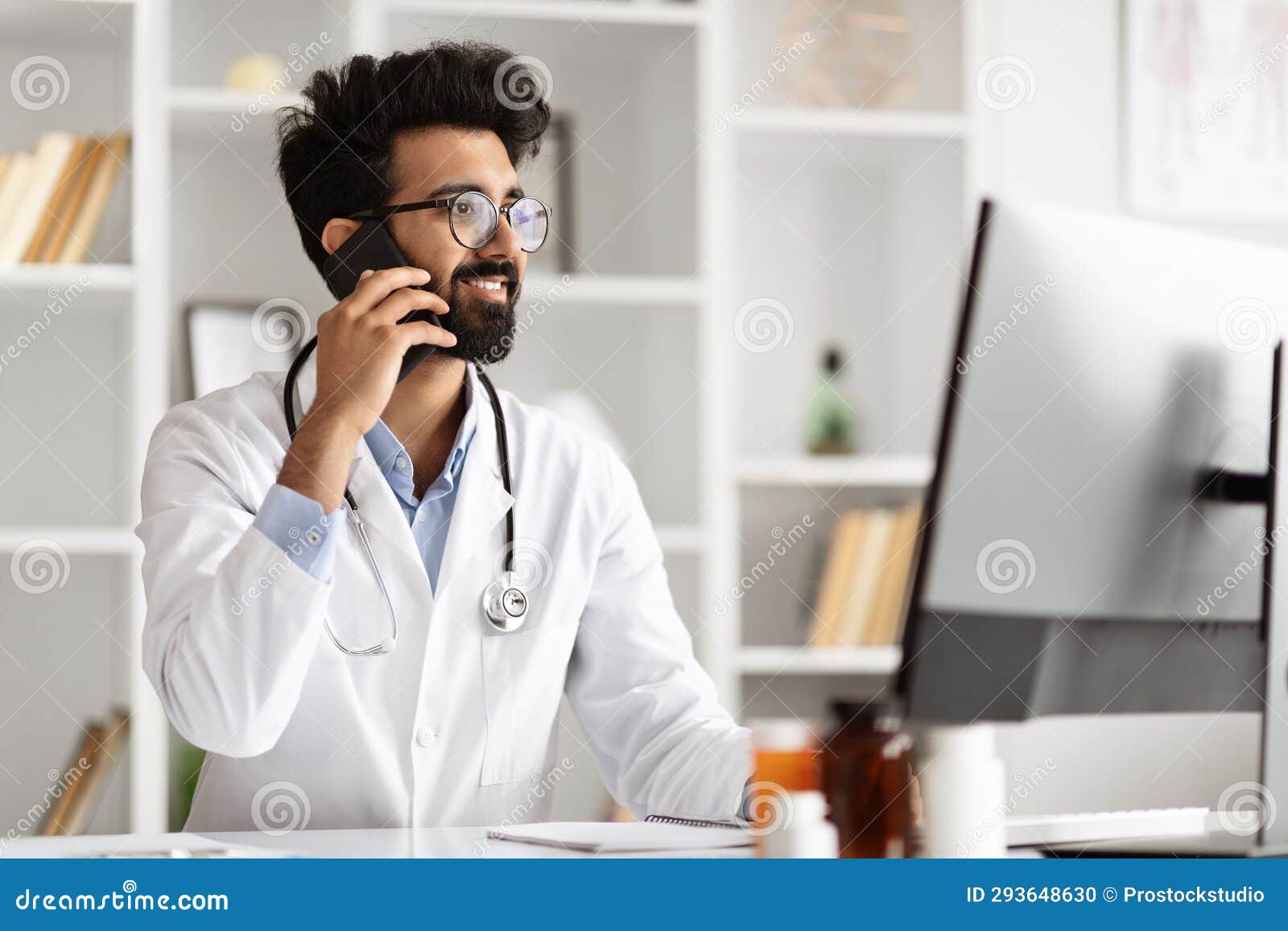 Indian Doctor Multitasking with Computer and Phone at Clinic Stock ...