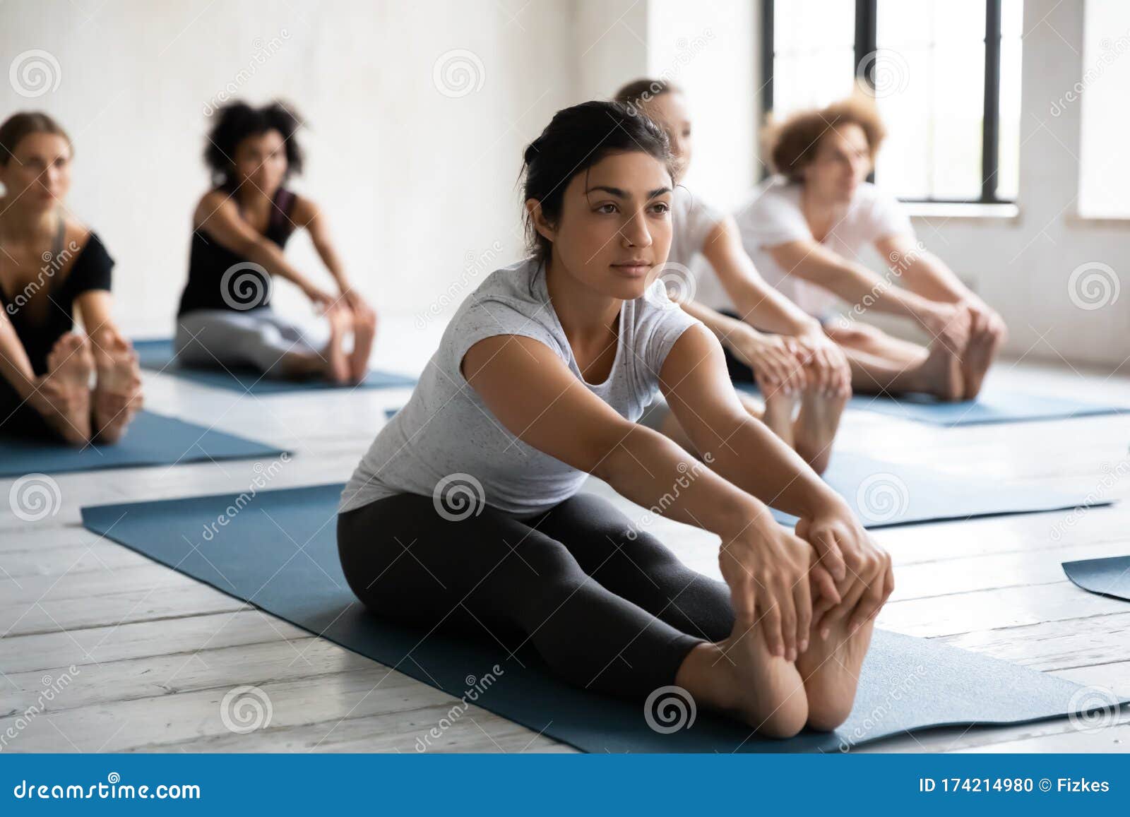 Indian Instructor and Group of People Performing Seated Forward Bend ...