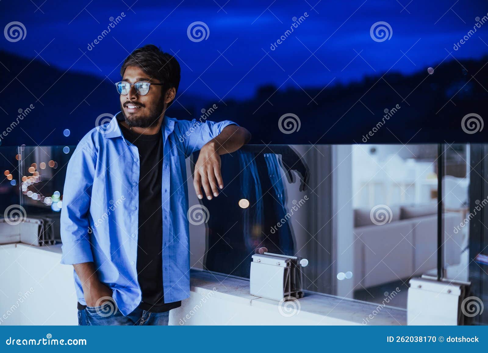 An Indian Man With Glasses And A Blue Shirt Looks Around The City At