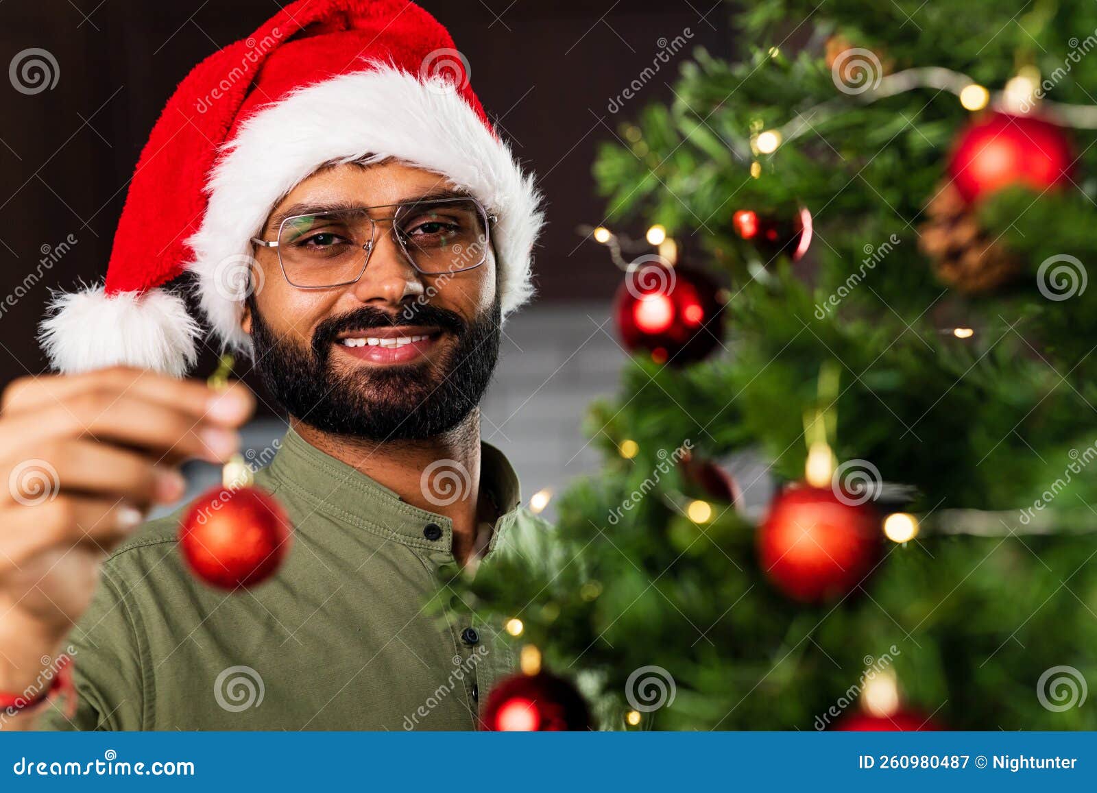 Indian Man in Santa Hat Decorating Christmas Tree with Baubles Stock ...