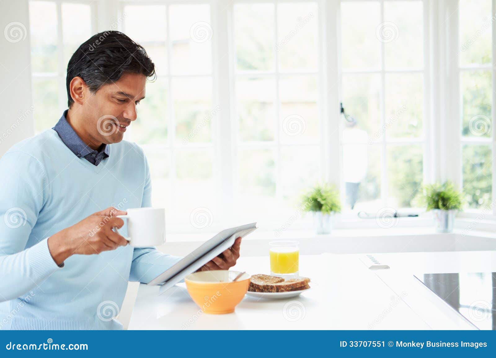 Indian Man Using Digital Tablet Whilst Eating Breakfast Stock Image ...