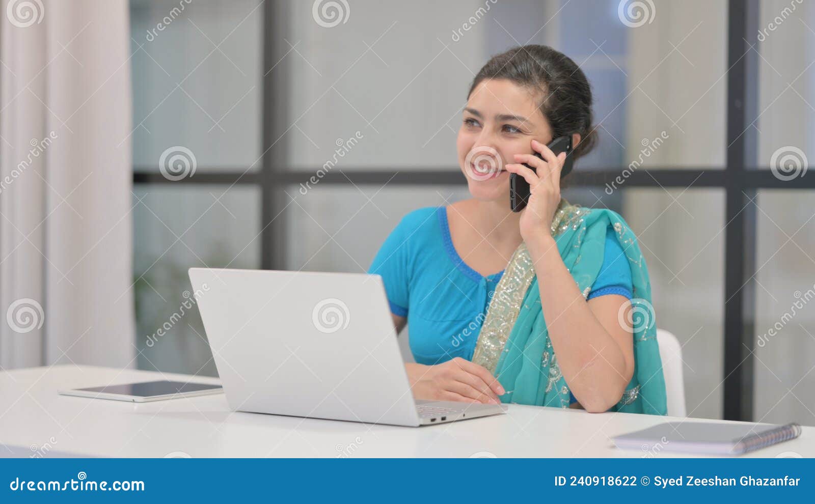 Indian Woman Talking on Phone while Using Laptop in Office Stock Photo ...