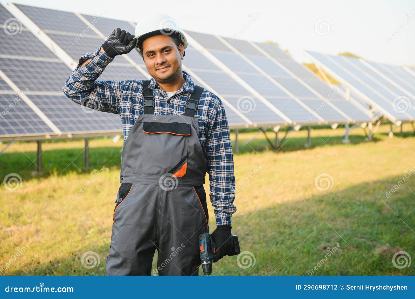 An Indian Worker in Uniform and with Tools Works on a Solar Panel Farm ...