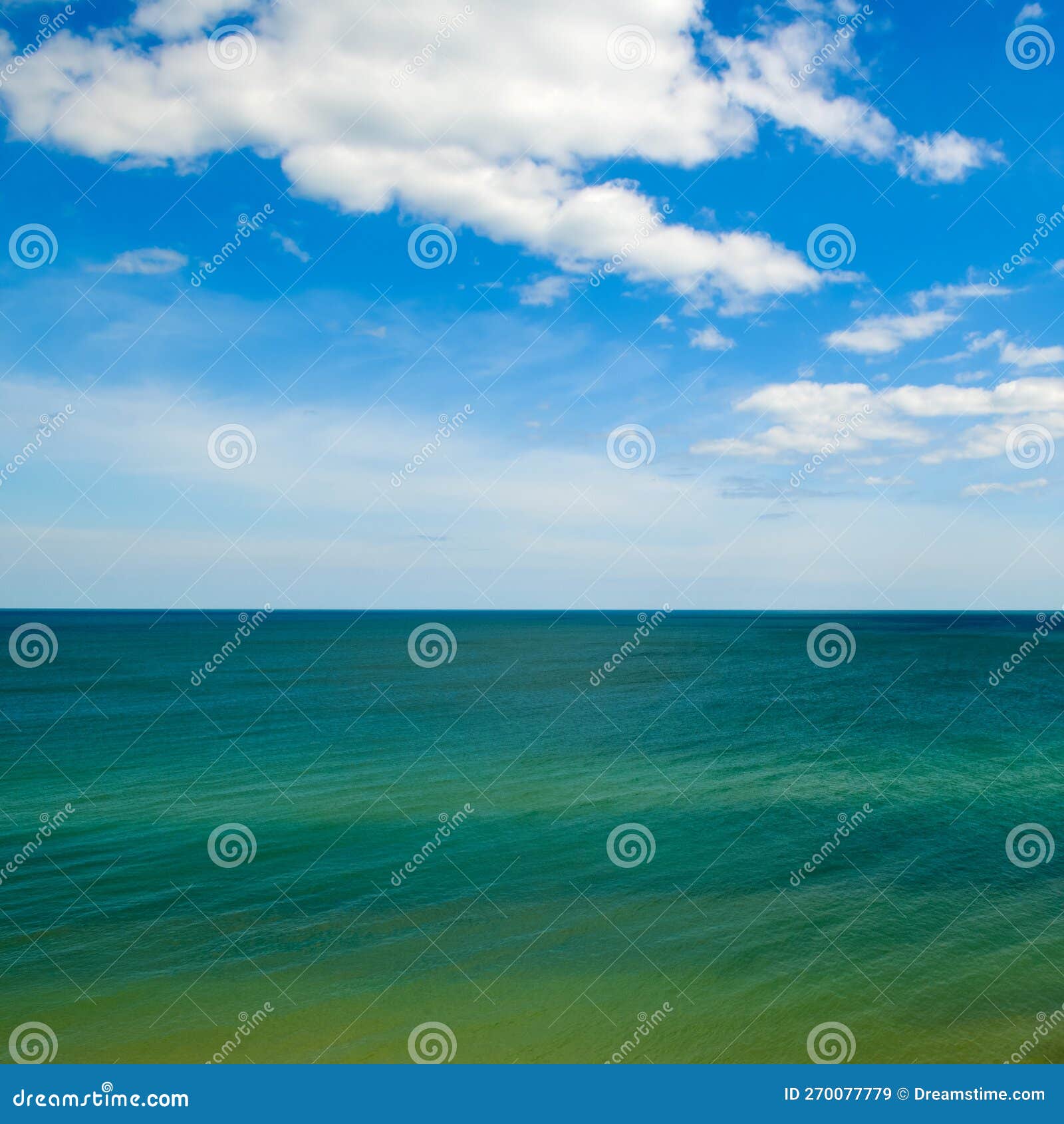 An Indigo Ocean and a Bright Blue Sky with White Clouds Stock Image ...