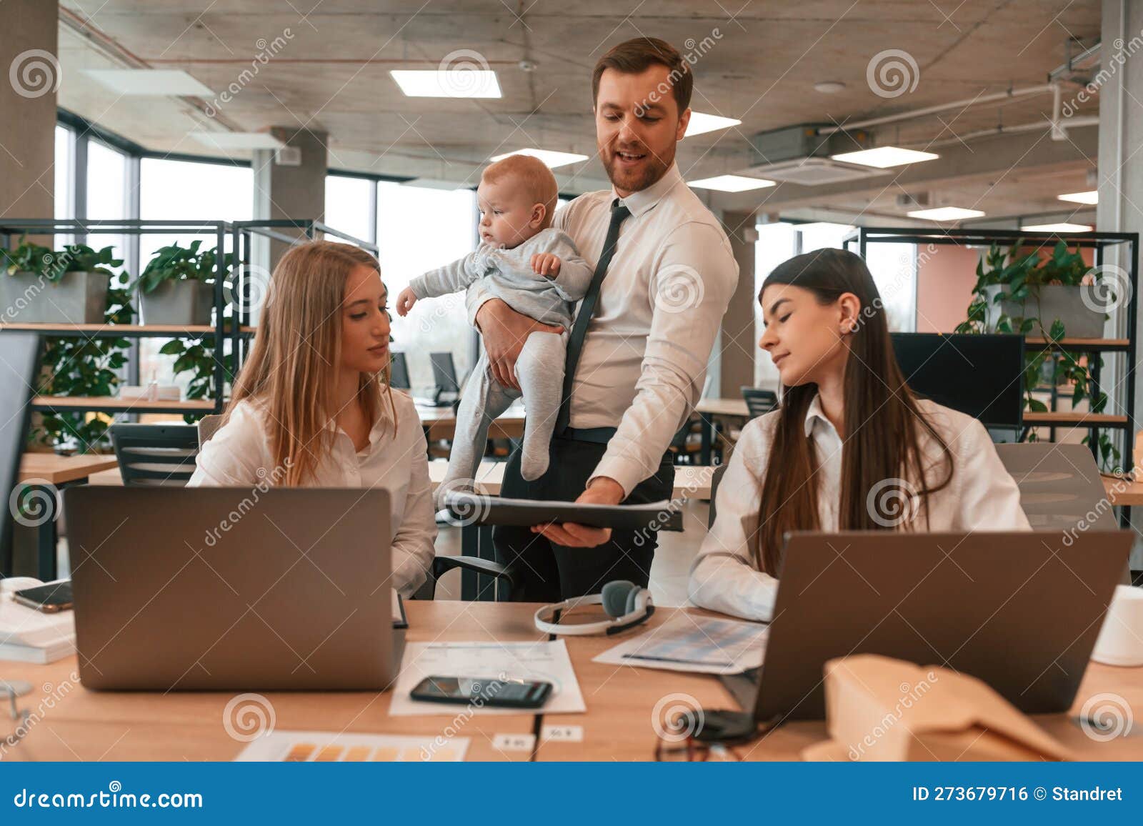 Infant Baby is in the Office Where Group of People are Working Together ...