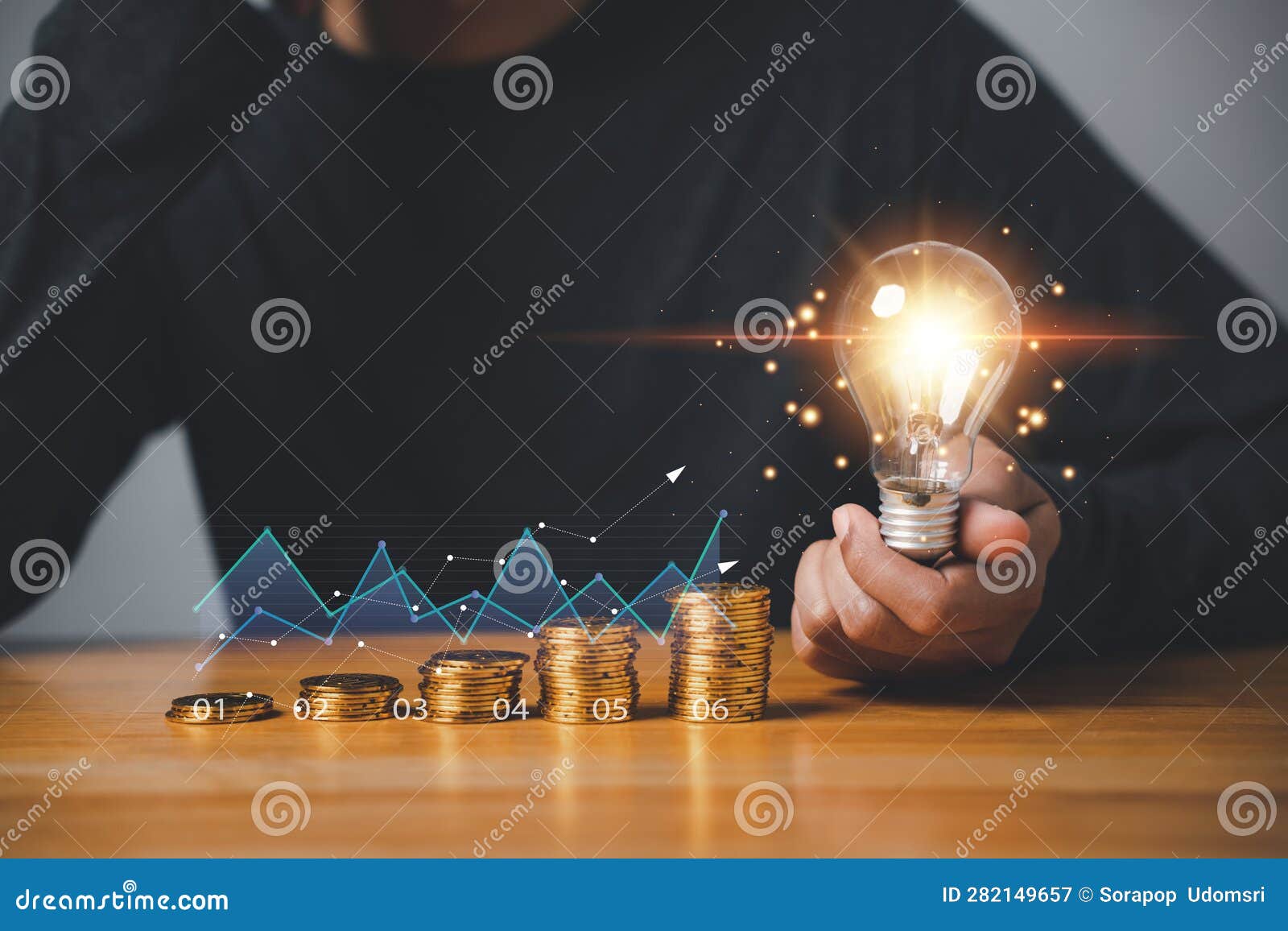 Hand Holding a Light Bulb with Coins Stack and Chart Graph Stock Image ...