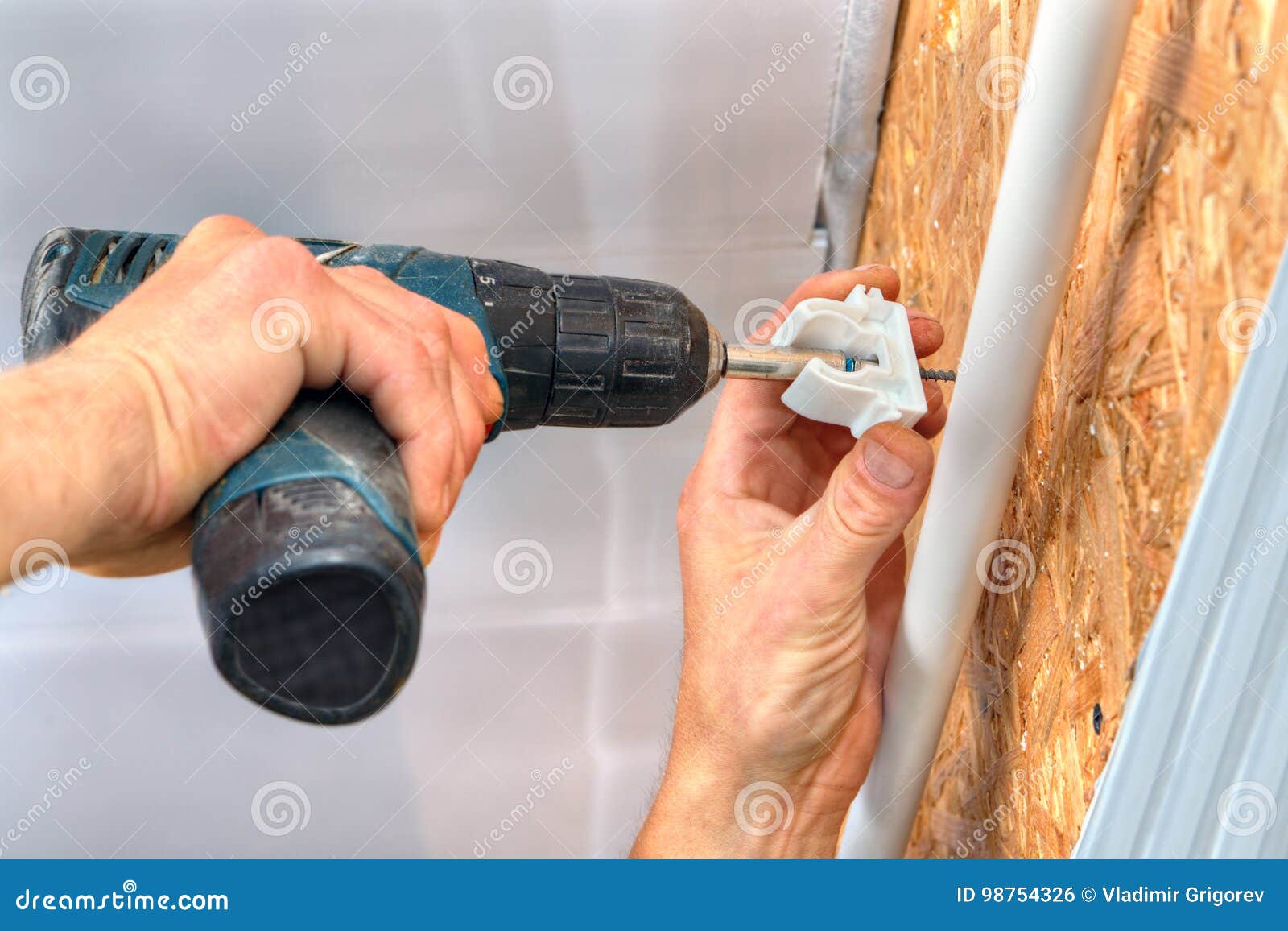 Fixing Clamp for Pipes on the Wall Using a Screwdriver. Stock Photo ...