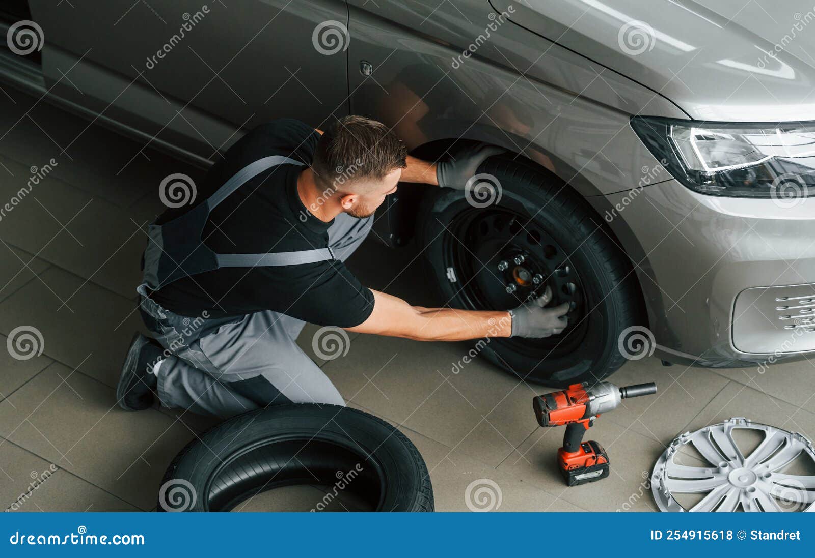 Installing New Tire. Man in Uniform is Working in the Autosalon at ...