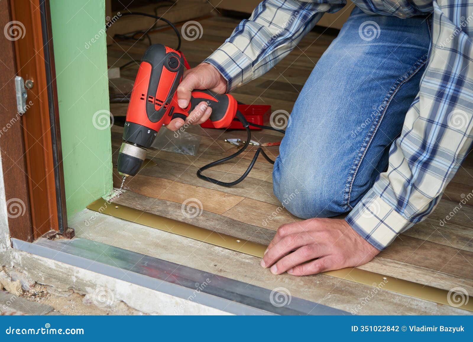 Installing a Threshold in the Door, Builder with a Drill Installs a ...
