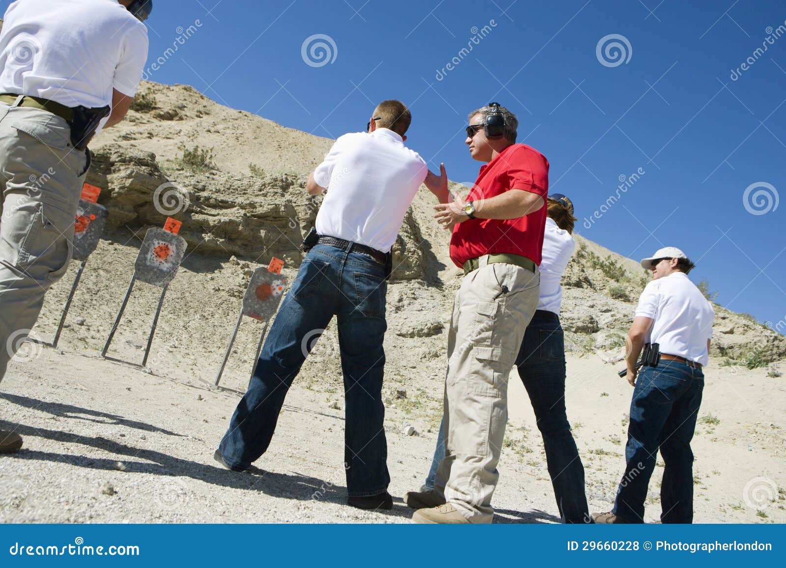 Instructor Assisting People Aiming Guns at Firing Range Stock Photo ...