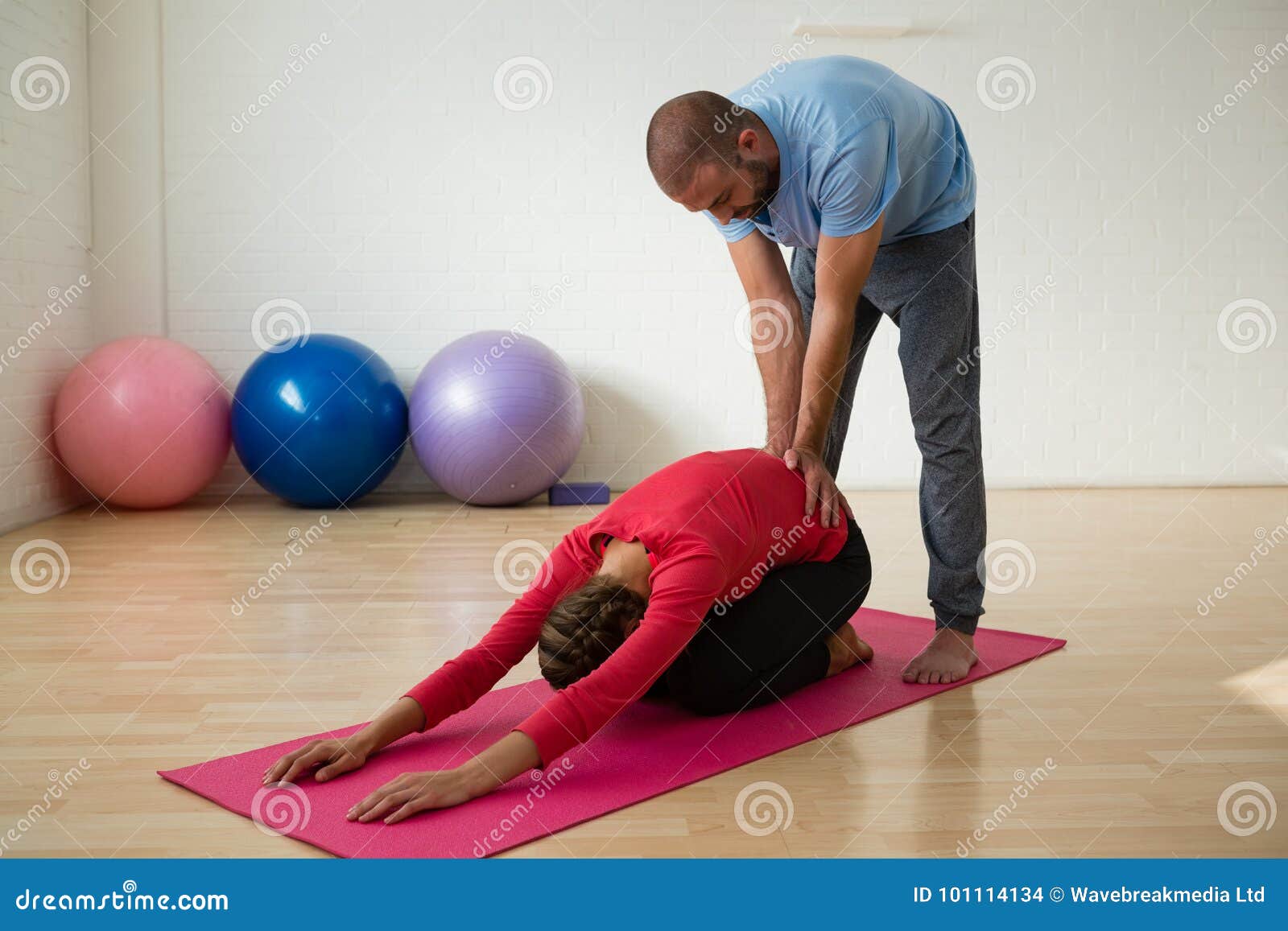 Instructor Assisting Student in Doing Child Pose at Studio Stock Photo ...