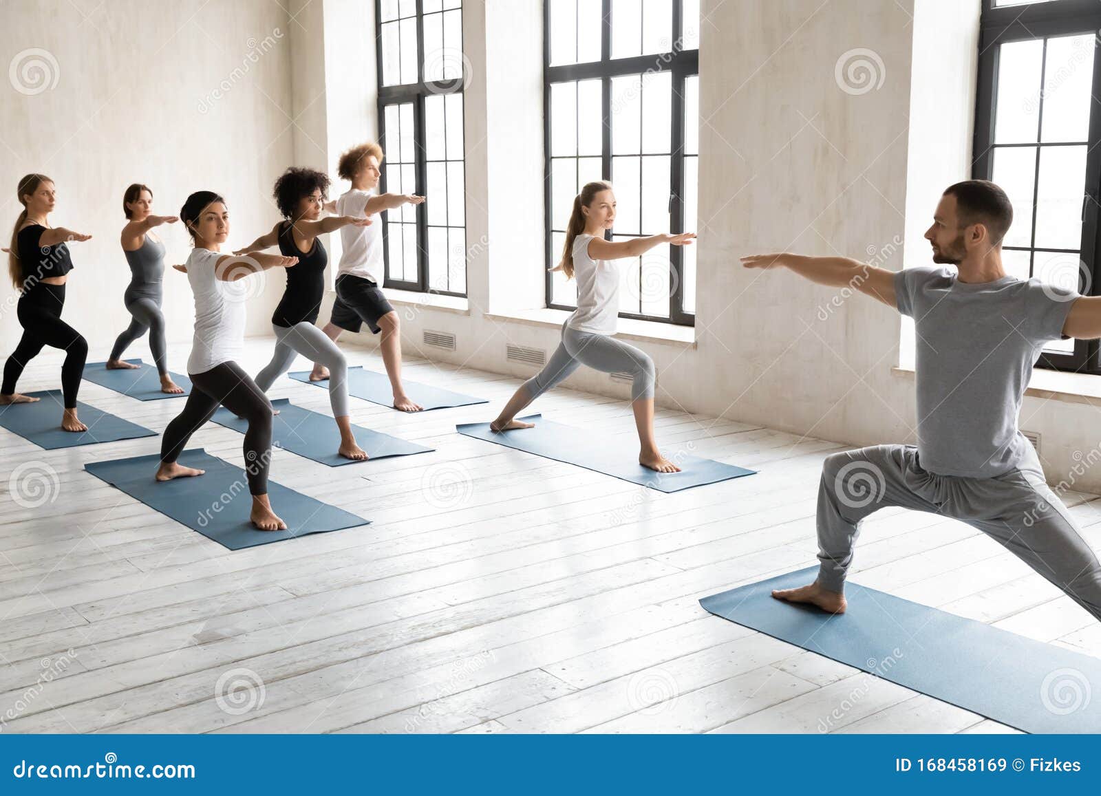 Instructor with Diverse People Practicing Yoga, Doing Warrior Two ...