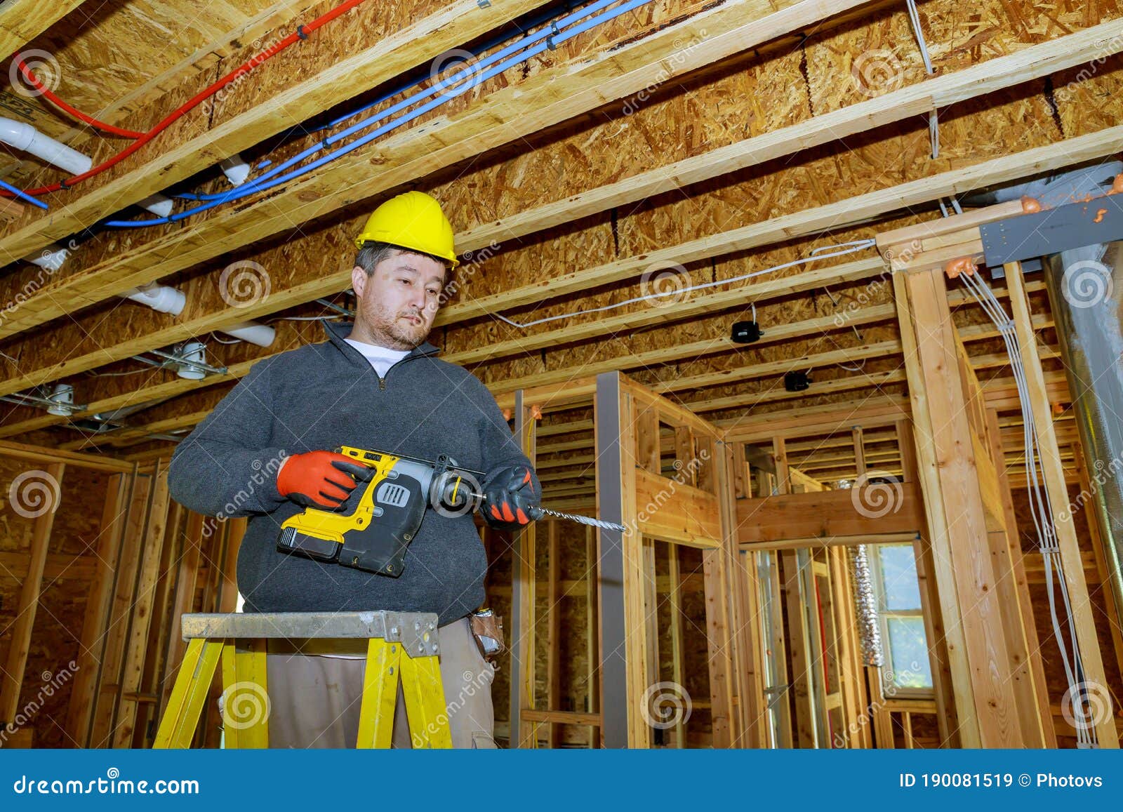 Interior Frame of a New House Under Construction Worker Drills Hole ...