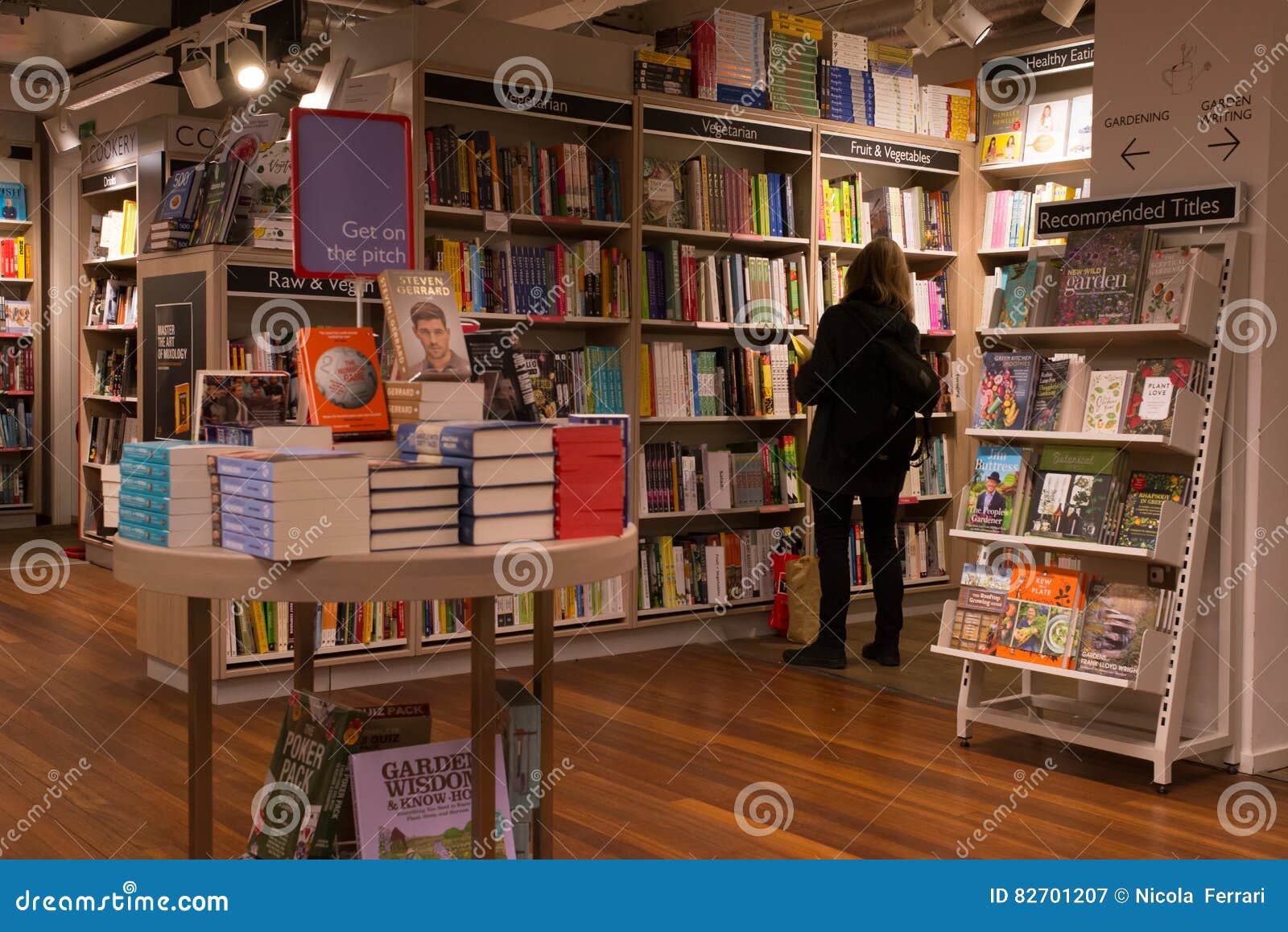 Interior of a Modern Bookshop with Woman Browsing the Collection ...