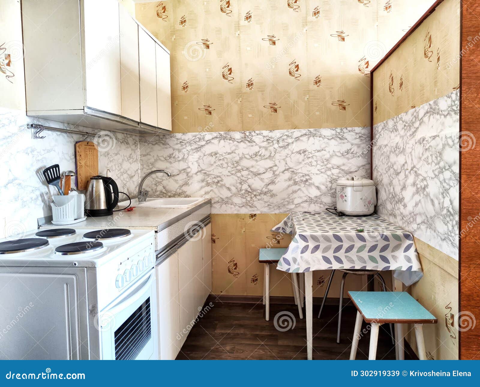 The Interior is a Small Old Kitchen with a Table, Stool, Cabinets, Sink and Stove. Design in the ...