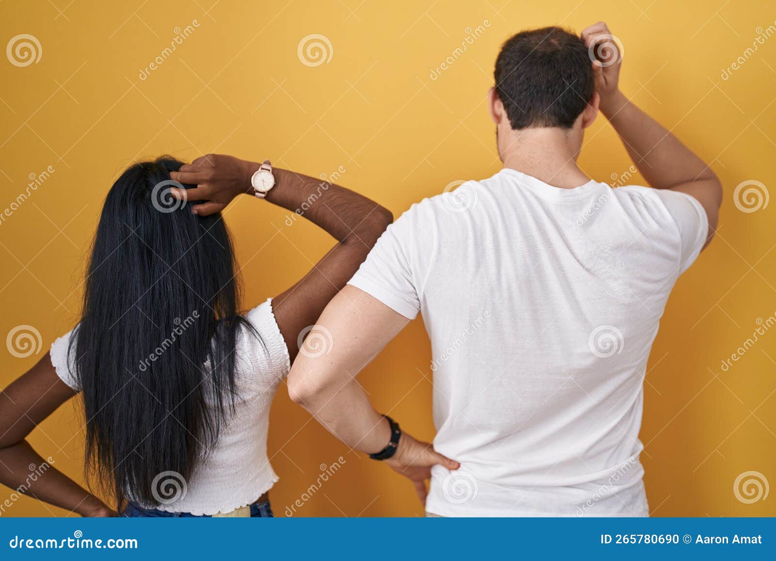 Interracial Couple Standing Over Yellow Background Backwards Thinking