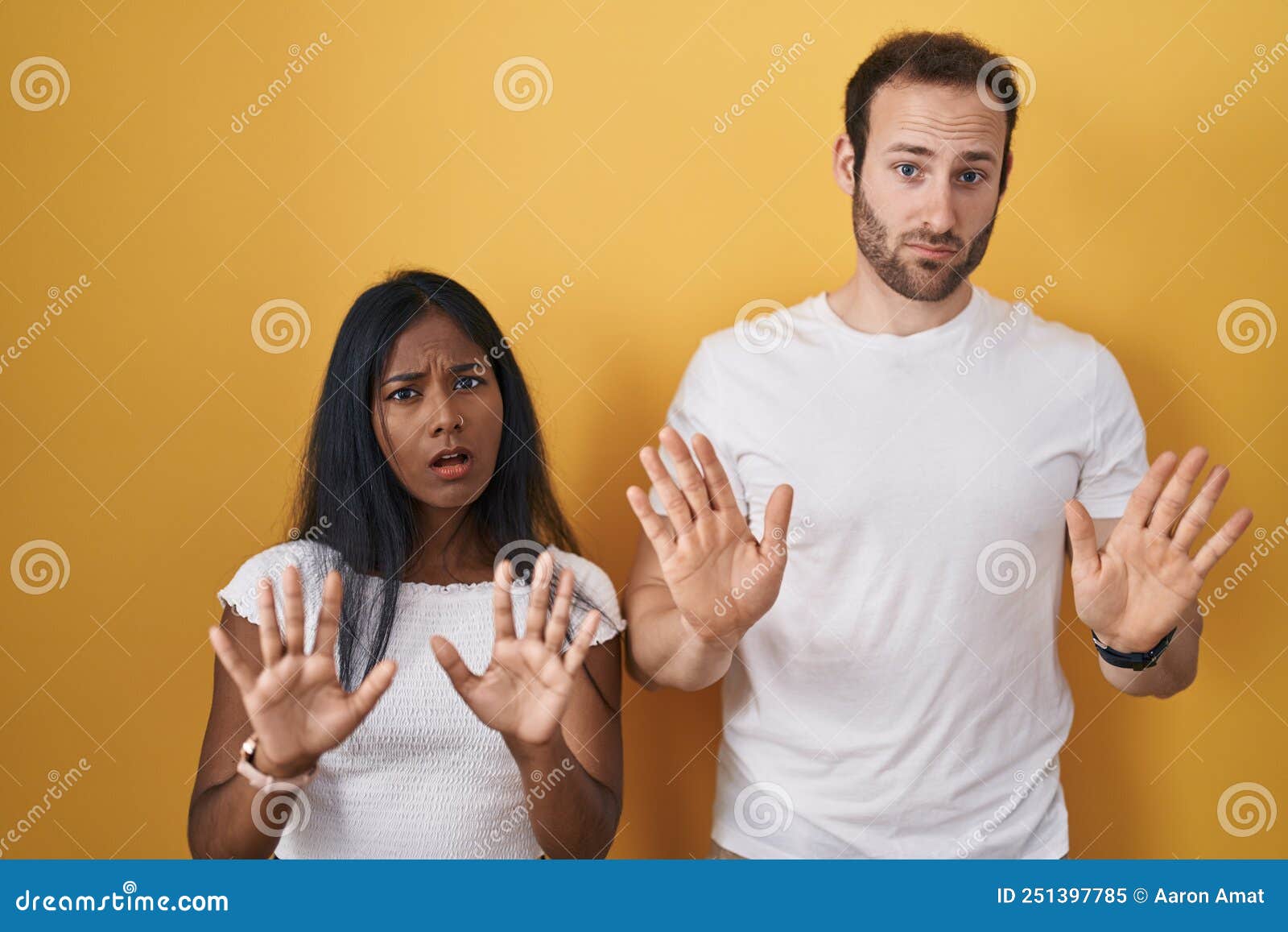 Interracial Couple Standing Over Yellow Background Moving Away Hands