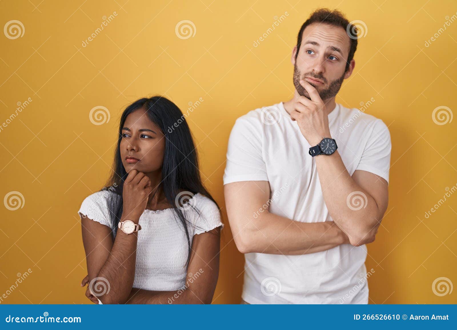 Interracial Couple Standing Over Yellow Background Thinking Worried