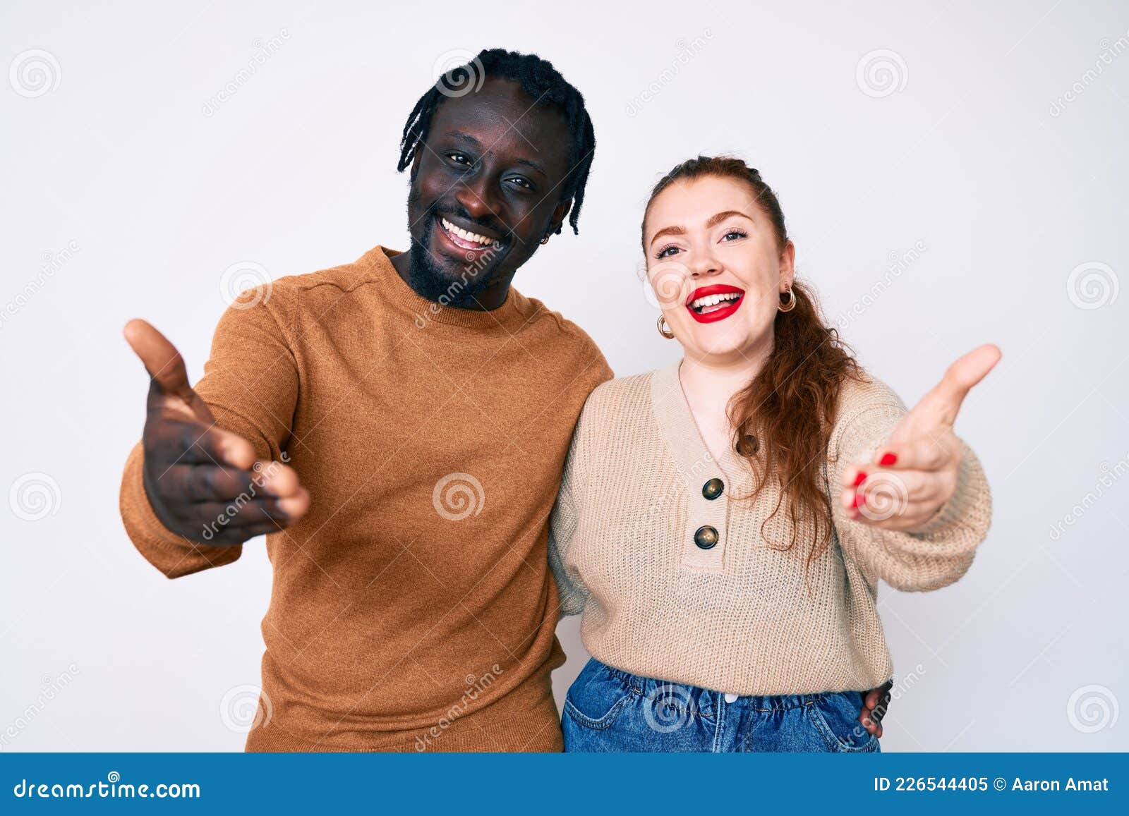 Interracial Couple Wearing Casual Clothes Smiling Friendly Offering