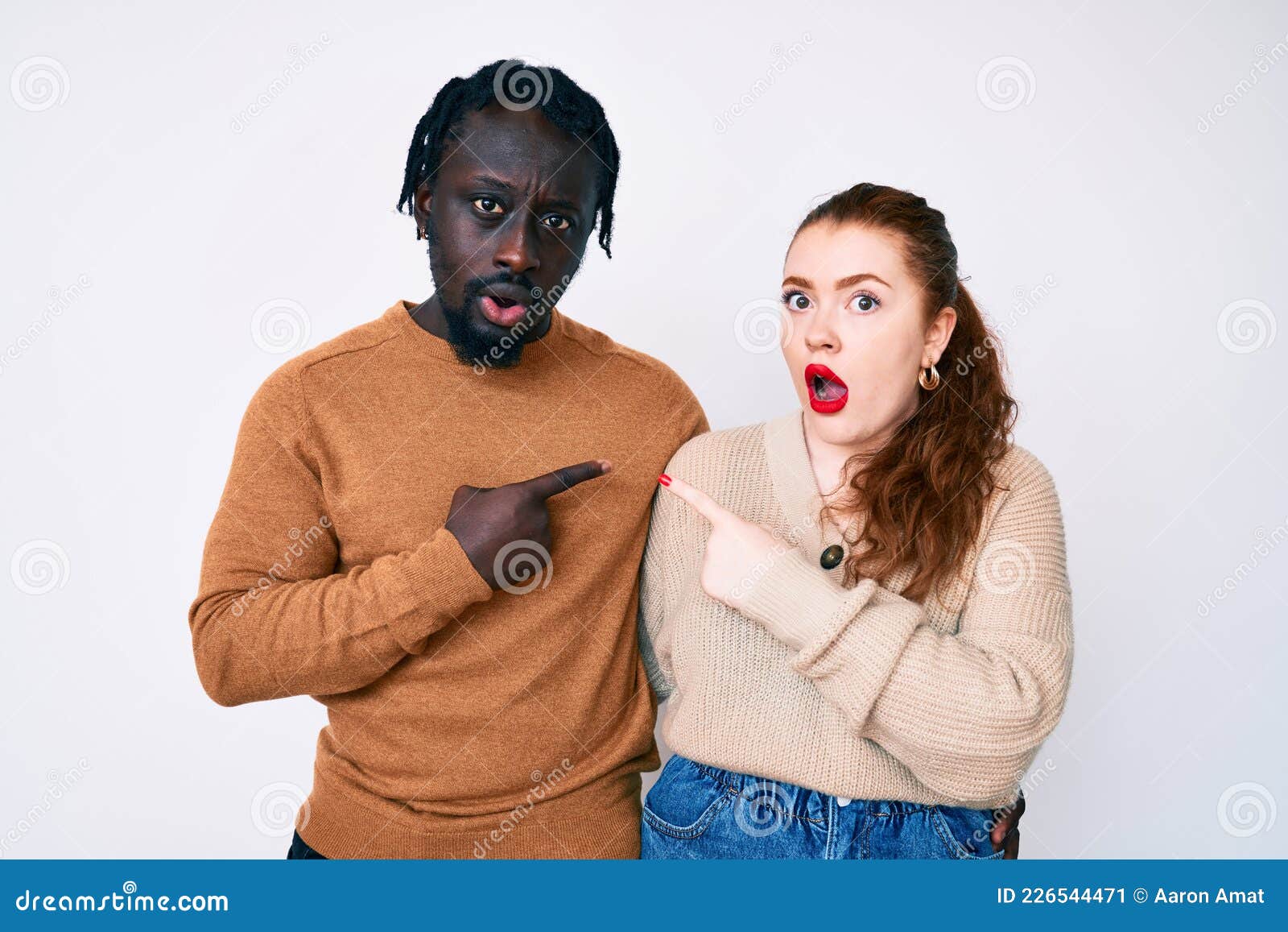 Interracial Couple Wearing Casual Clothes Surprised Pointing With