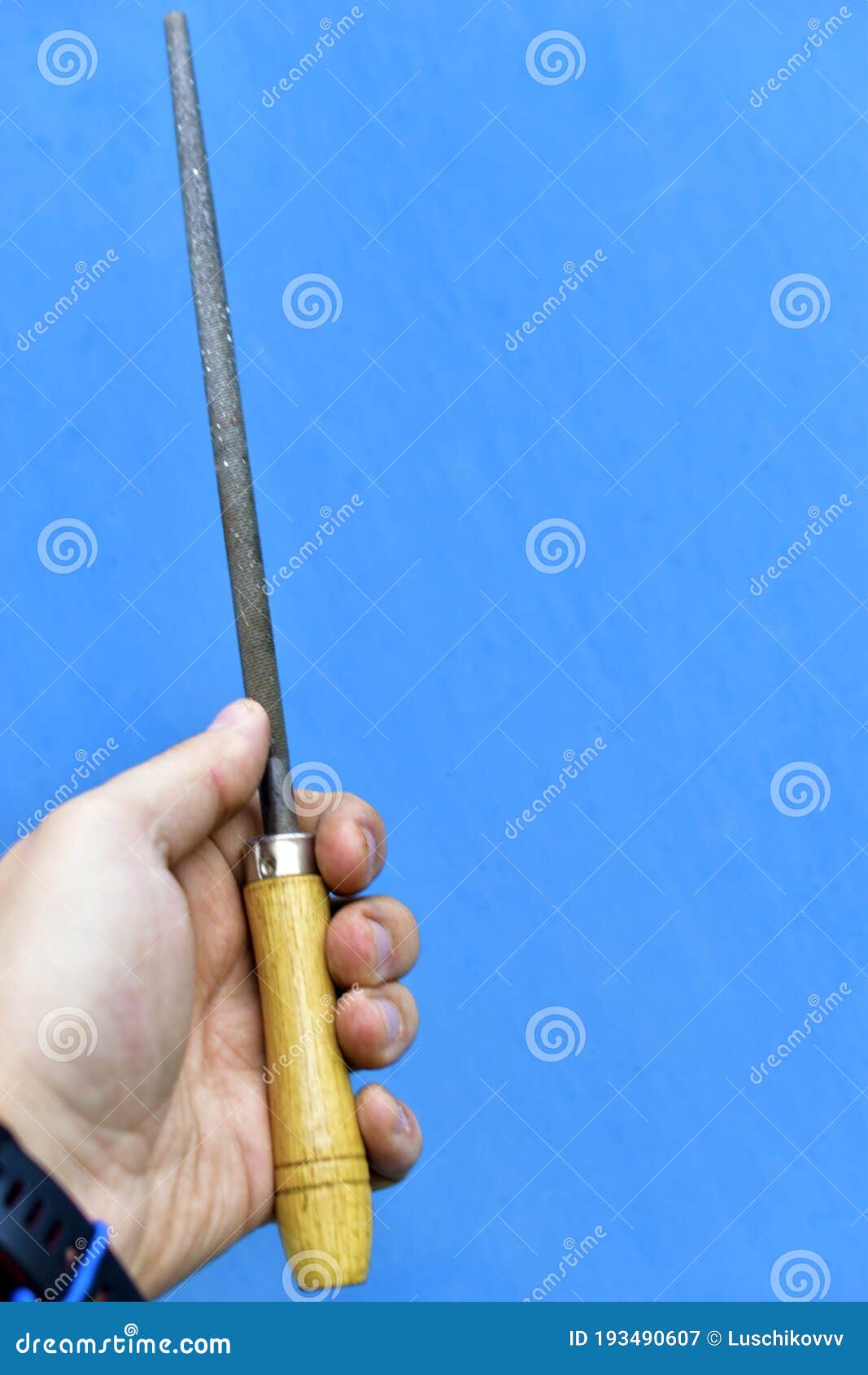 Iron Round File with Wooden Handle in Hand on Blue Background Stock ...