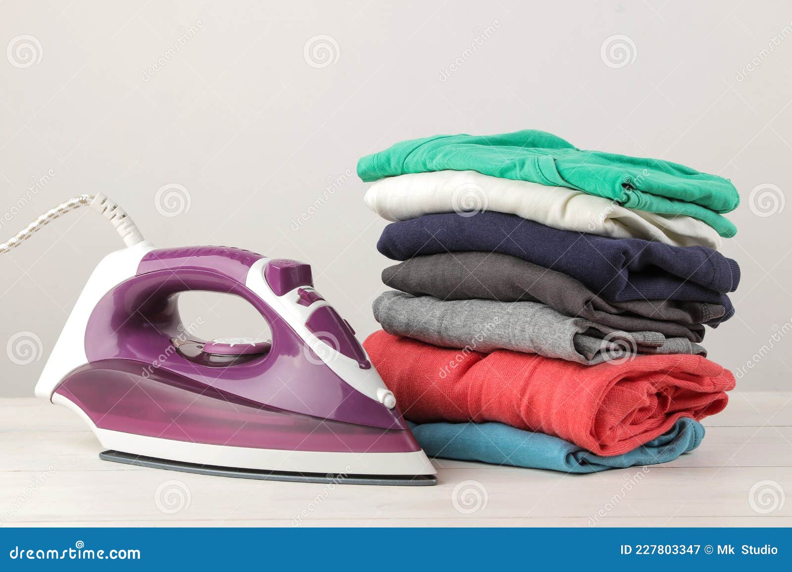 Iron and a Stack of Colored Clothes on a White Background. Ironing of ...
