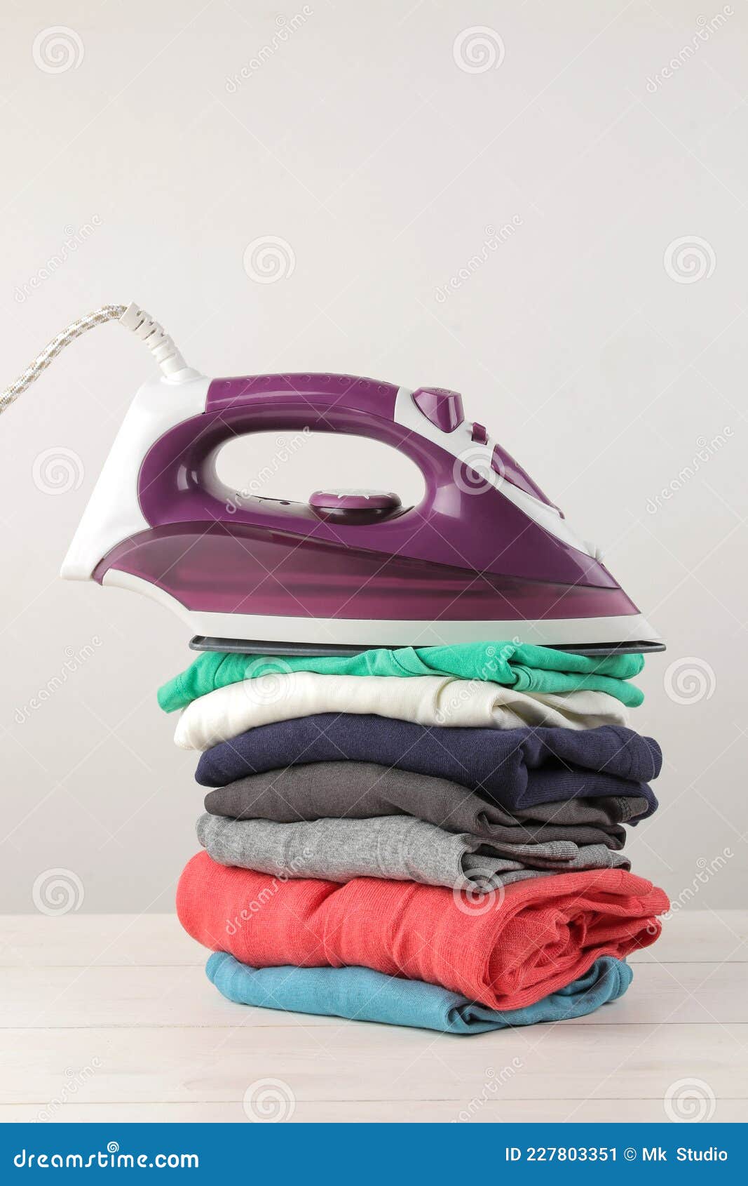 Iron and a Stack of Colored Clothes on a White Background. Ironing of ...