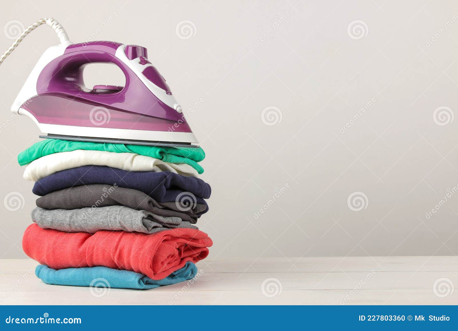 Iron and a Stack of Colored Clothes on a White Background. Ironing of ...