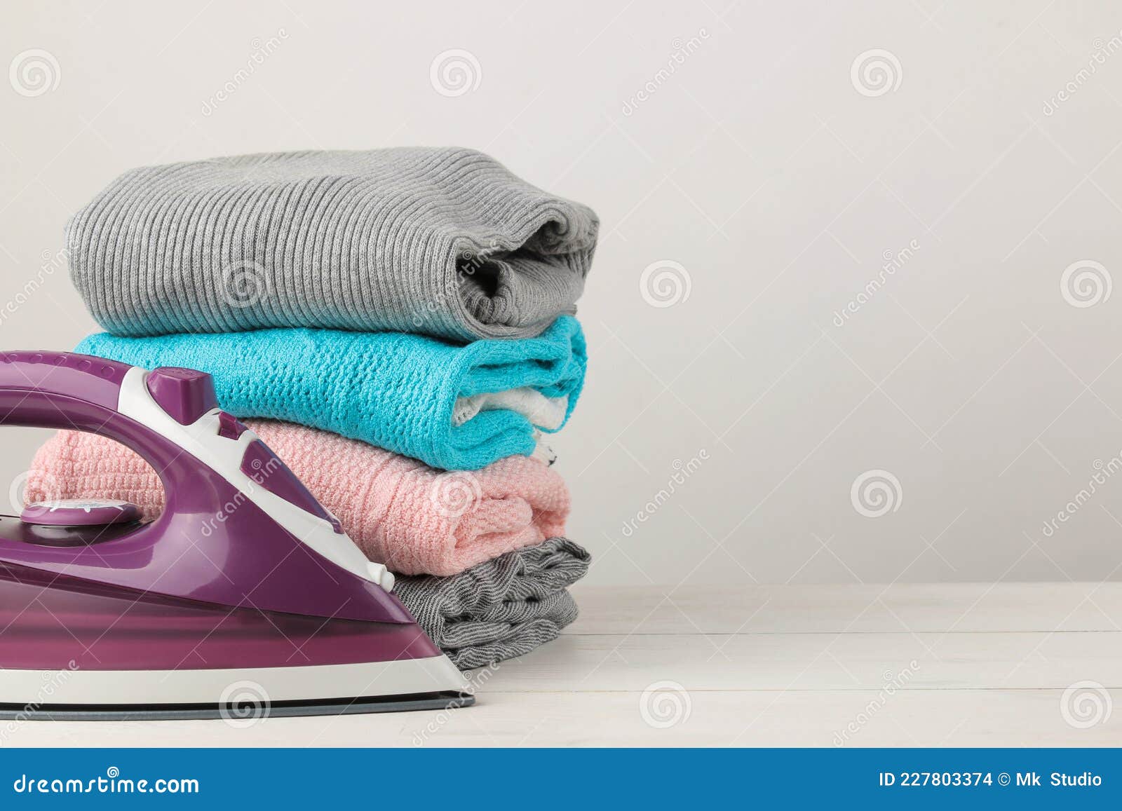 Iron and a Stack of Colored Clothes on a White Background. Ironing of ...